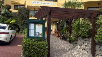 Hotel com restaurante, bar e jardim, incluindo uma pérgula e um caminho de pedra.