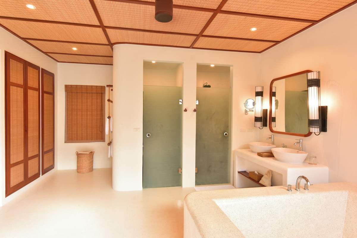 Casa de banho moderna com uma banheira grande, duas pias e um espelho amplo.