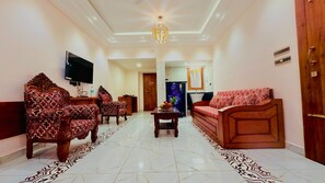 Sala de estar com sofás estampados, televisão e luminária decorativa no teto.