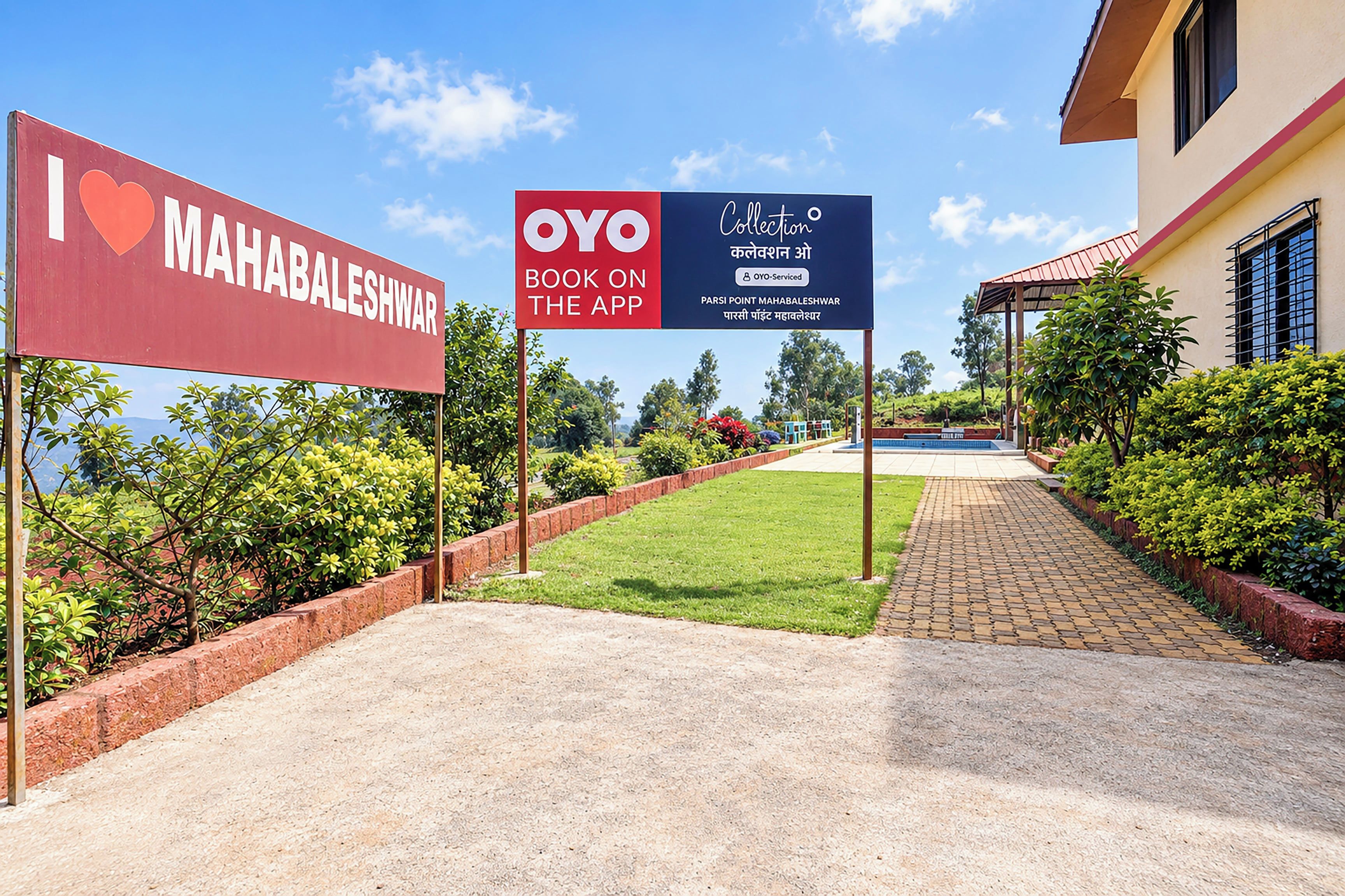 Uma trilha leva a um edifício com uma placa indicando serviço de reservas para um local chamado Mahabaleshwar.