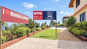 Uma trilha leva a um edifício com uma placa indicando serviço de reservas para um local chamado Mahabaleshwar.