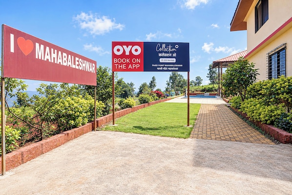 Uma trilha leva a um edifício com uma placa indicando serviço de reservas para um local chamado Mahabaleshwar.