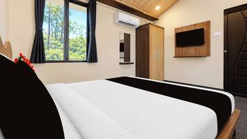 Quarto de hotel com cama, televisão na parede, aparelho de ar condicionado e janela com cortinas.