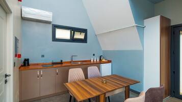 Cozinha compacta com mesa e cadeiras, forno embutido e janela com persianas.
