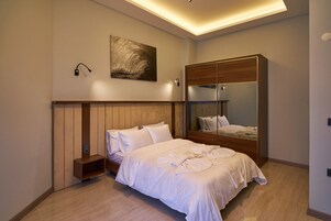 Quarto de hotel com cama, mesa de cabeceira e um espelho grande.