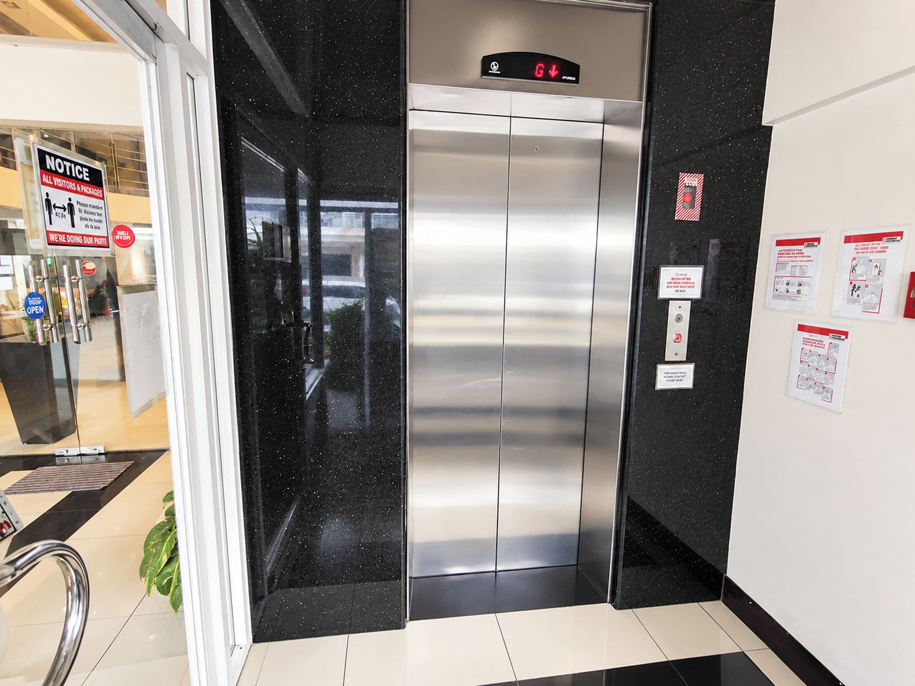 Um elevador com visor digital, aviso e instruções de emergência na parede.