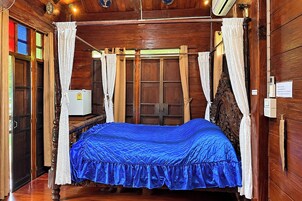 Quarto com cama, paredes de madeira, janela e porta.