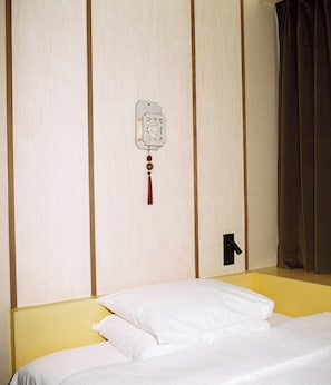 Quarto de hotel com cama, interruptor de luz na parede e cortina.