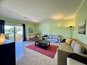 Uma sala de estar com sofá, mesa de centro e área de jantar com cadeiras e mesa.