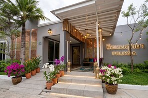 Entrada de um edifício com uma placa indicando 'PRUKSA' e degraus que levam até ele.