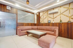 Uma sala de estar moderna com parede de madeira, um sofá rosa, um banquinho combinando e uma mesa de centro decorativa.