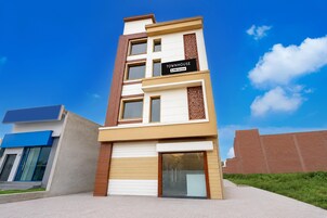 Uma casa geminada moderna com telhado plano, janelas amplas e uma placa indicando que é administrada pela Oyo.