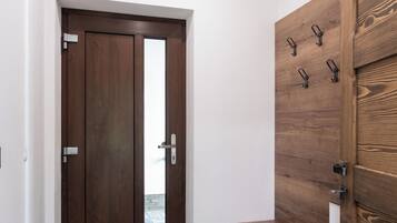 Corredor com porta de madeira, um banco e um cabideiro na parede.