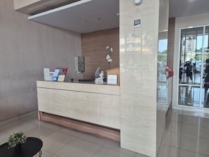 Uma receção com design moderno, um ecrã digital e um sinal a indicar o serviço 'KOTOKU'.