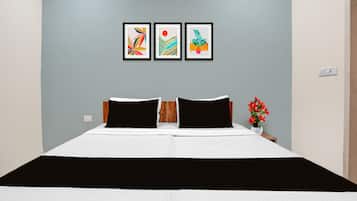 Uma cama com roupa de cama preta e branca, um painel de cabeceira de madeira e uma mesa de cabeceira com um vaso de flores vermelhas.