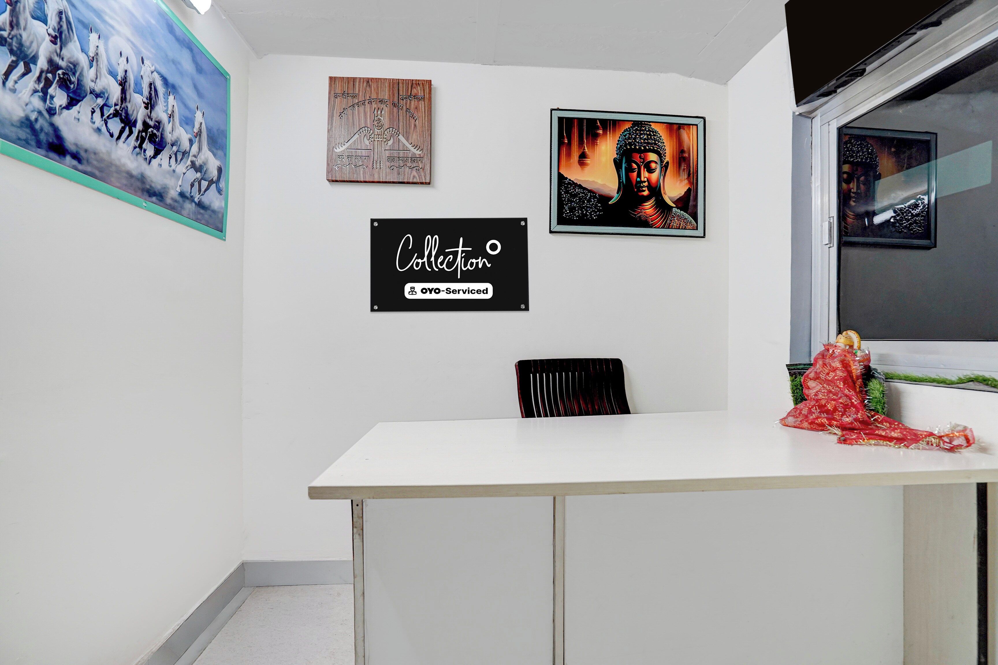 Quarto com uma escrivaninha branca, uma pintura emoldurada de Buda e uma pintura emoldurada de um cavalo na parede.