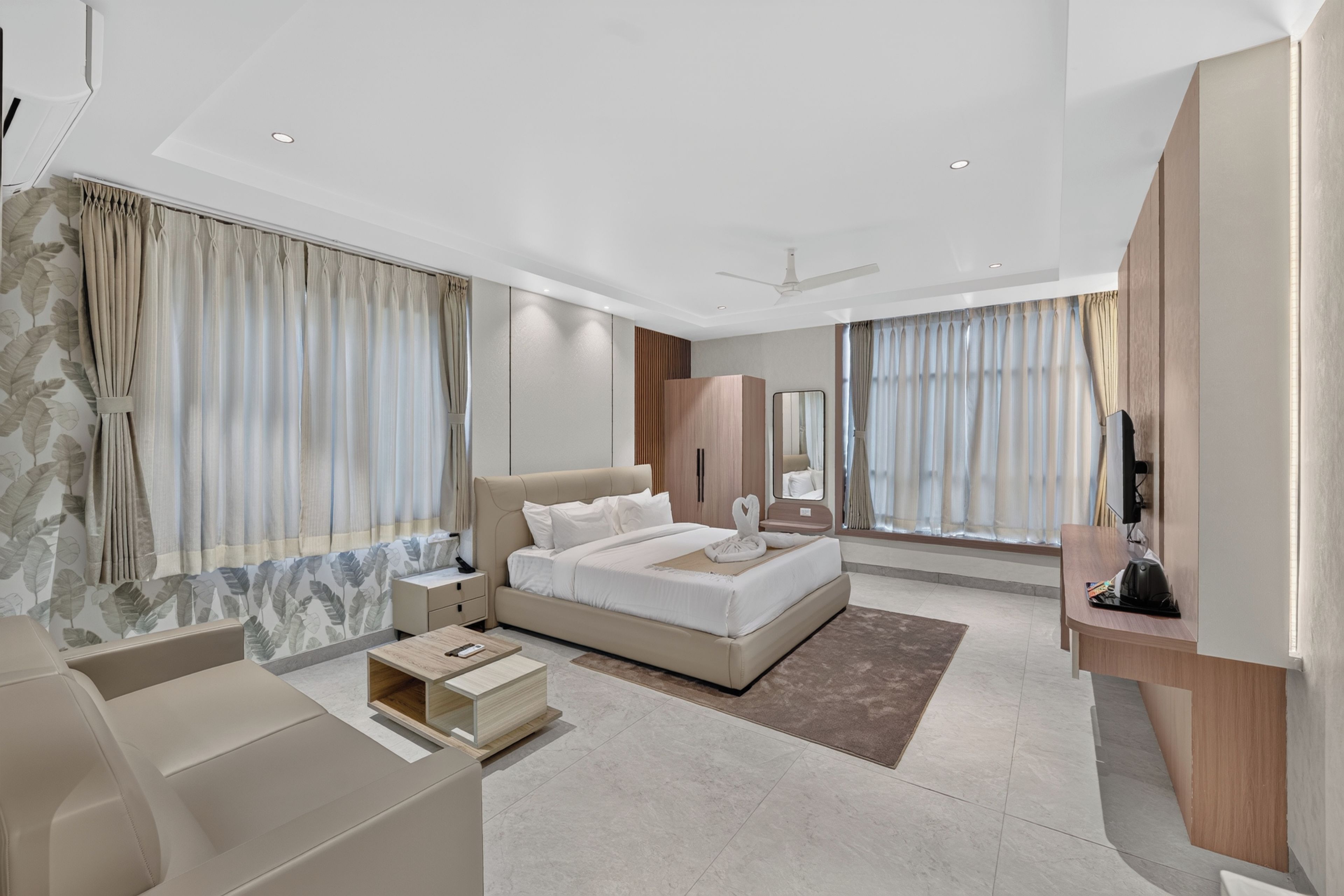Quarto de hotel moderno com uma cama grande, uma escrivaninha, uma cadeira e uma televisão.