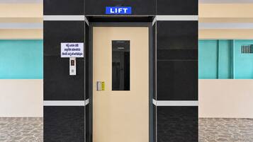 Um elevador com uma placa indicando 'LIFT' acima da porta, um visor digital e uma placa na parede com a inscrição 'PULL'.
