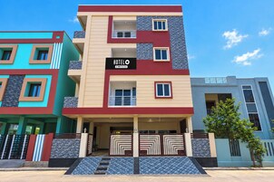 Um hotel com várias andares e fachada moderna, com uma placa indicando que é administrado pela OYO, e uma entrada com portão.