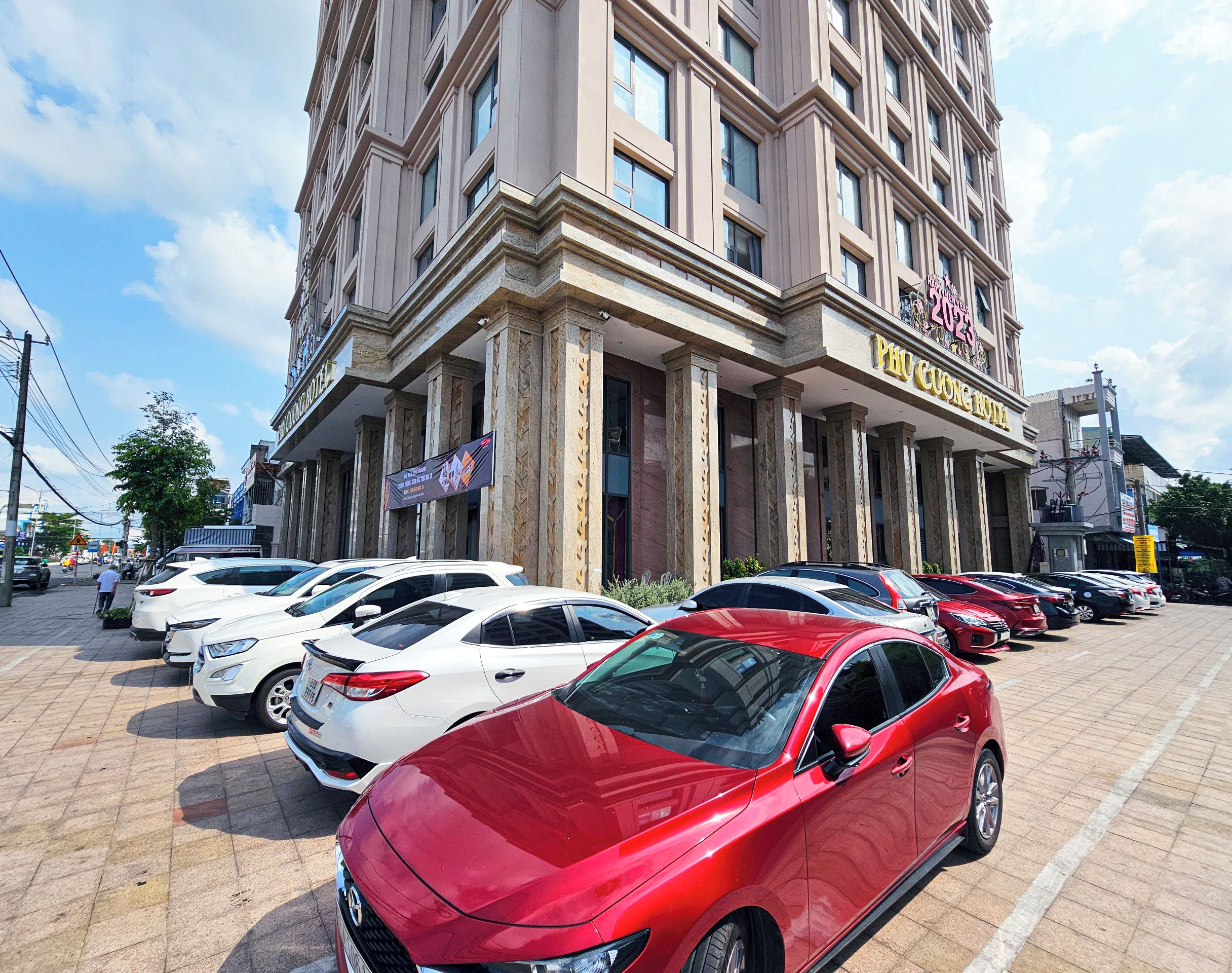 Hotel com fachada moderna, vários espaços de estacionamento e céu claro.