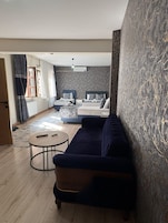 Uma sala de estar moderna com sofá, mesa de centro e cama com cabeceira.