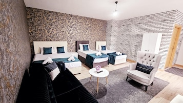 Quarto de hotel moderno com uma cama grande, duas camas menores, um sofá, uma poltrona e uma mesa pequena.