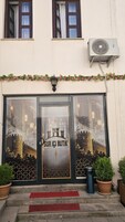 Entrada de hotel com porta de vidro exibindo ilustração de castelo e o texto 'SUR İÇİ BUTIK'.