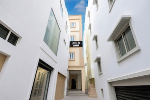 Um beco estreito entre dois edifícios brancos, com uma placa indicando um hotel.
