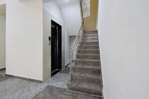 Escada com corrimão de metal que leva a uma porta com moldura preta.