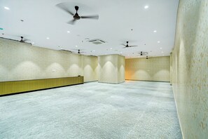 Quarto espaçoso com paredes padronizadas, vários ventiladores de teto, iluminação embutida e um radiador ao longo de uma parede.