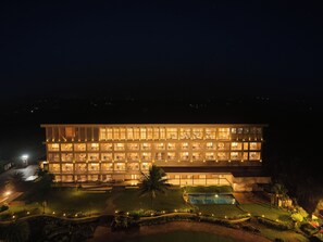 Um hotel com vários andares, piscina e áreas externas bem iluminadas.