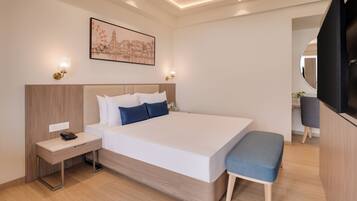 Quarto de hotel moderno com cama grande, mesas de cabeceira, escrivaninha e televisão.