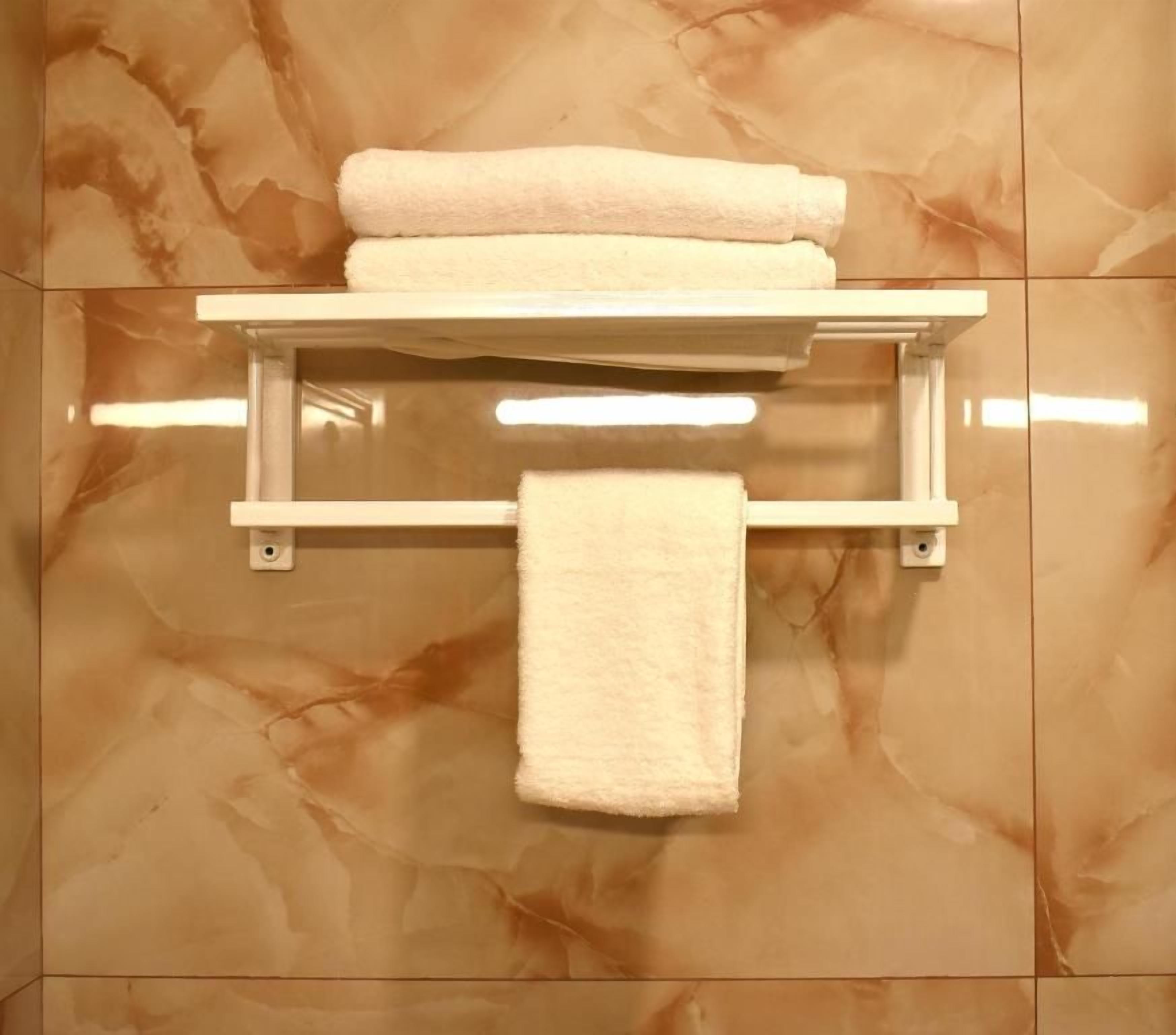 Casa de banho com toalheiro branco com duas toalhas dobradas e uma toalha suspensa.