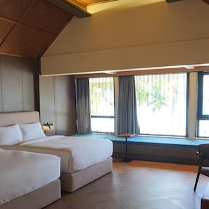 Quarto moderno com uma cama grande, janela com cortinas e vista para o verde lá fora.