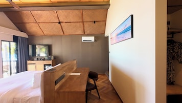 Quarto de hotel com cama, escrivaninha, cadeira, televisão e ar condicionado.
