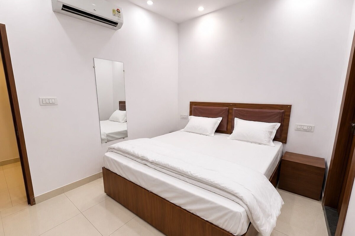 Quarto com cama, mesa de cabeceira, espelho e ar condicionado.