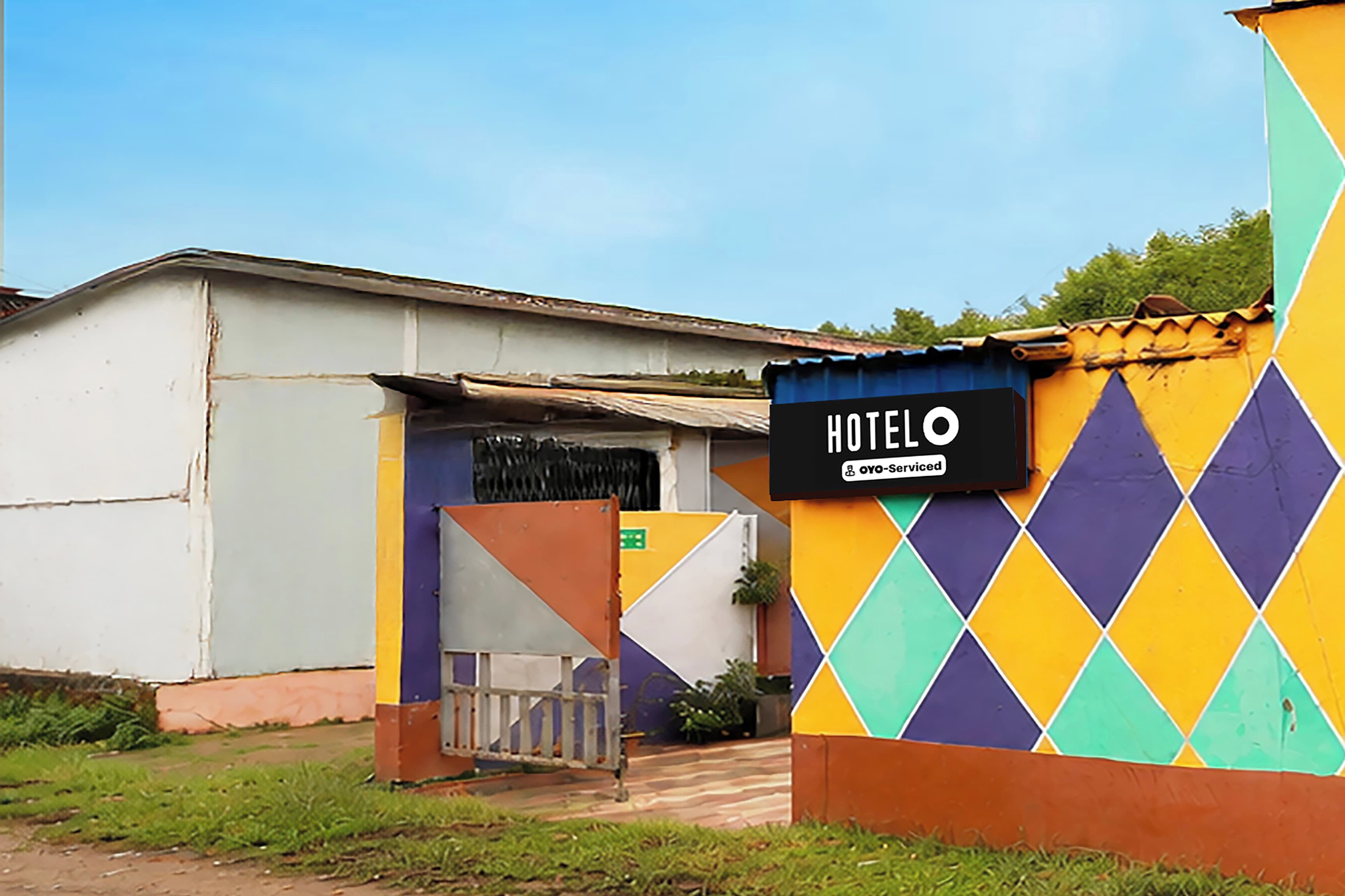 Entrada de hotel com portão colorido e placa indicando serviço OYO.