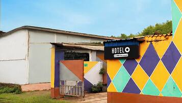 Entrada de hotel com portão colorido e placa indicando serviço OYO.
