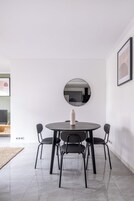 Uma zona de refeições moderna com uma mesa redonda, quatro cadeiras, um vaso e um espelho grande na parede.