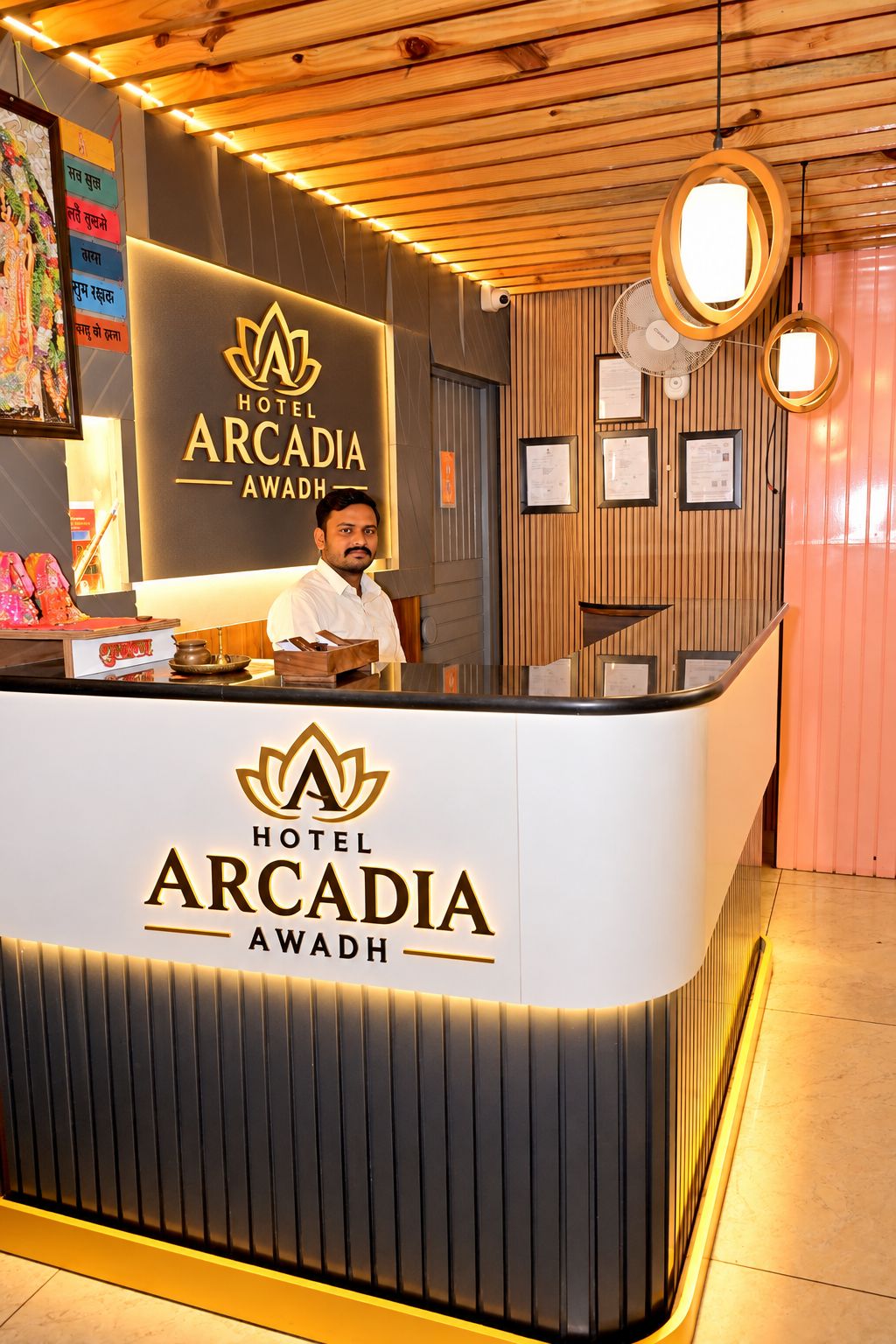 Balcão de recepção no Hotel Arcadia Awadh, com design moderno, certificados emoldurados na parede e teto de madeira.