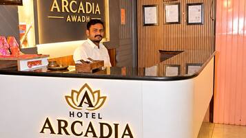 Balcão de recepção no Hotel Arcadia Awadh, com design moderno, certificados emoldurados na parede e teto de madeira.