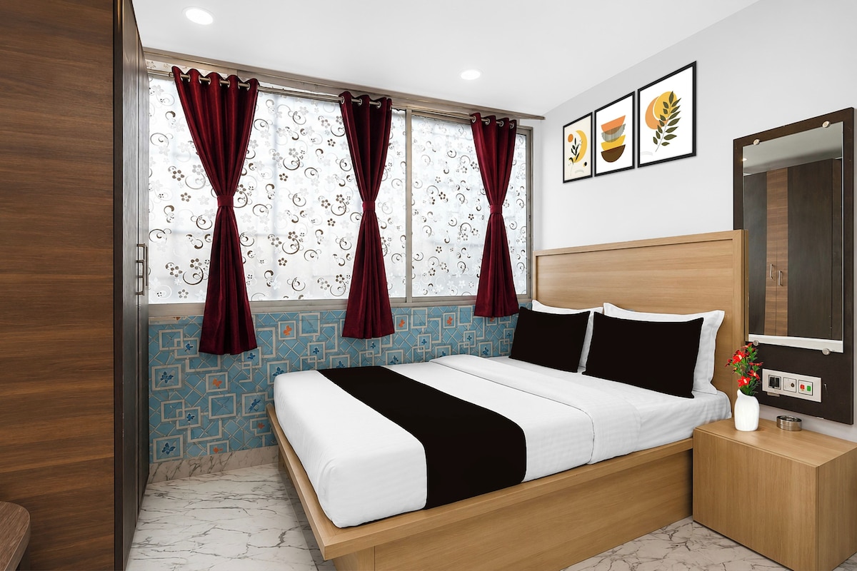 Quarto moderno com cama, cortinas, mesa de cabeceira, espelho e decoração na parede.