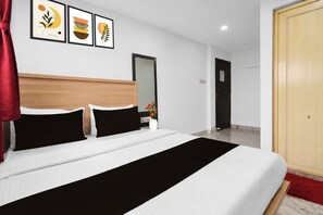 Quarto de hotel com cama, espelho, porta e decoração na parede.