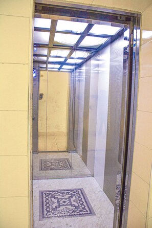Um elevador com piso estampado, paredes de vidro e teto com claraboias.