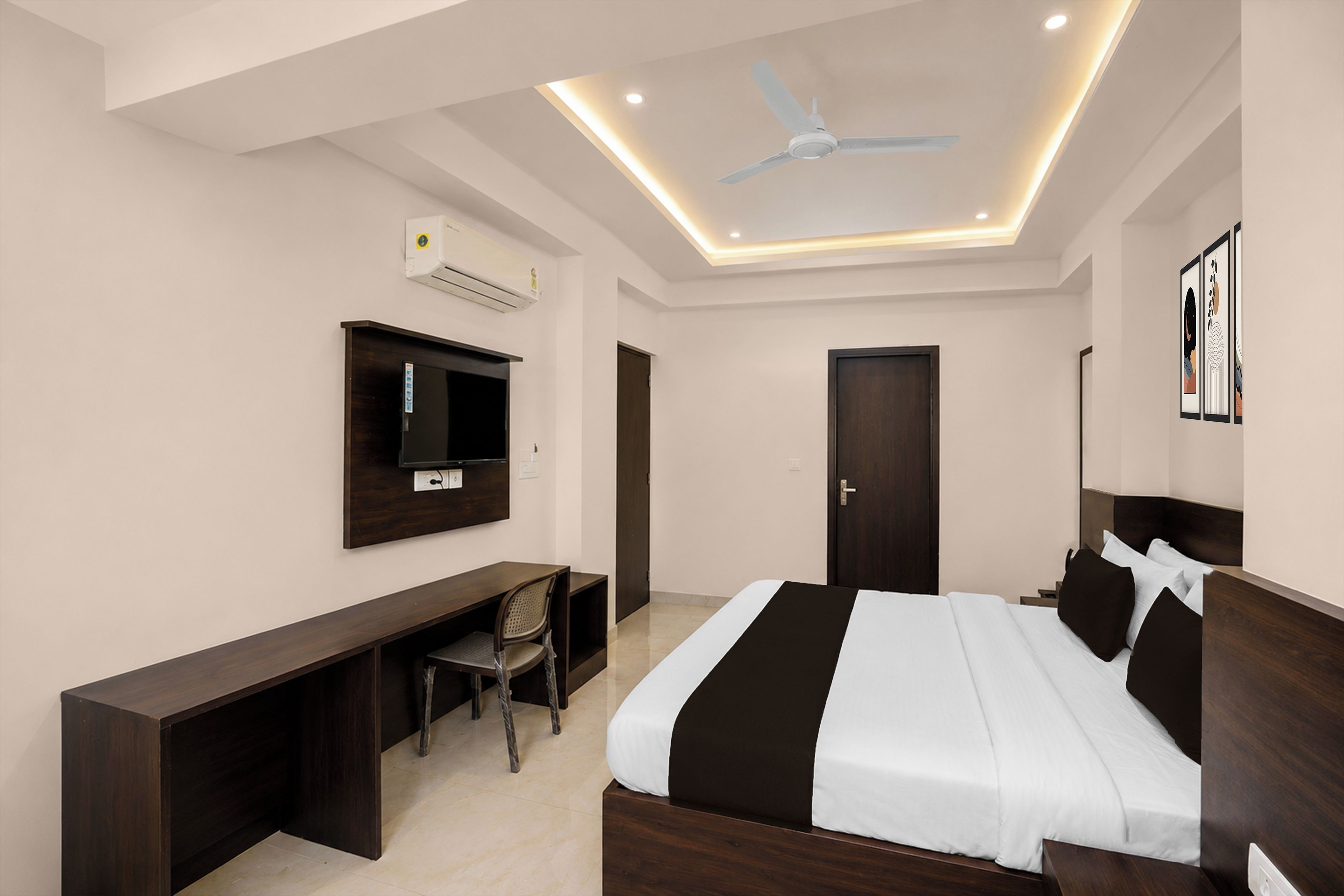 Quarto de hotel moderno com cama, escrivaninha, cadeira, televisão e ventoinha no teto.