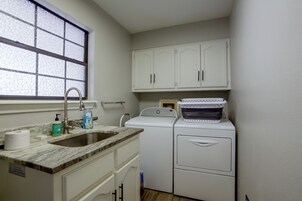Cozinha compacta com pia, bancada e máquina de lavar roupa.