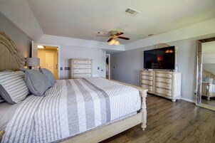 Quarto com cama, penteadeira, espelho e ventoinha no teto.