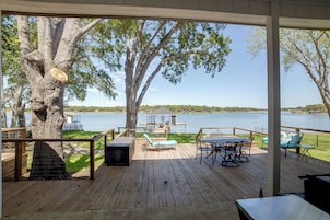 Um deck de madeira com móveis de exterior com vista para um lago.