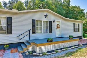 Uma casa térrea com varanda frontal, decoração em estrela sobre a porta e um pequeno jardim com pedras no chão e plantas.