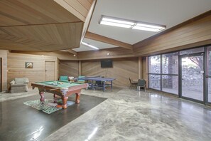 Quarto com mesa de bilhar, mesa de pebolim e mesa de sinuca.